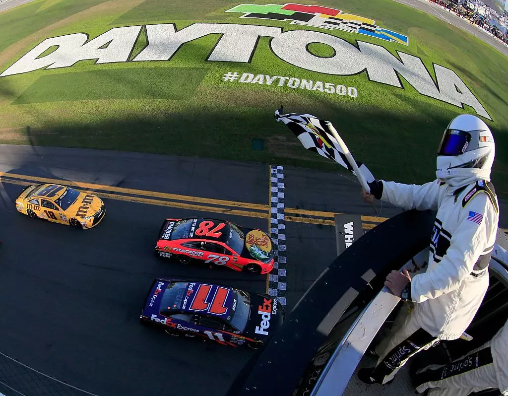 daytona beach, fl 21 febrewaris denny hamlin, sjauffeur fan 'e 11 fedex express toyota, nimt de geruite flagge foar martin truex jr, bestjoerder fan' e 78 bass pro shopstracker boats toyota, om de nascar sprint cup series daytona 500 te winnen op daytona international speedway op 21 febrewaris 2016 yn Daytona Beach, Florida foto troch Chris Trotmannascar fia Getty Images